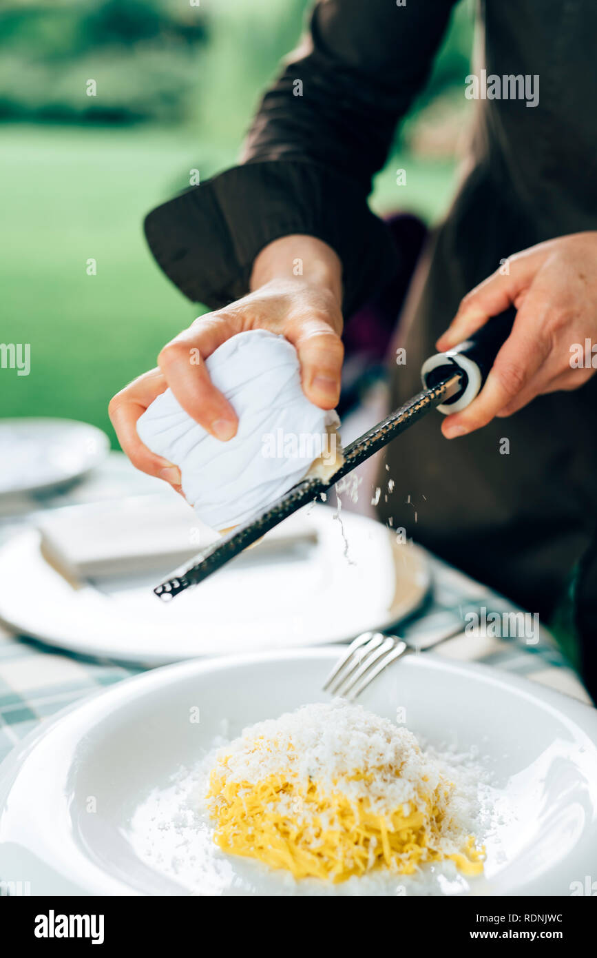 Waiter grating parmesan cheese on spaghetti Stock Photo - Alamy