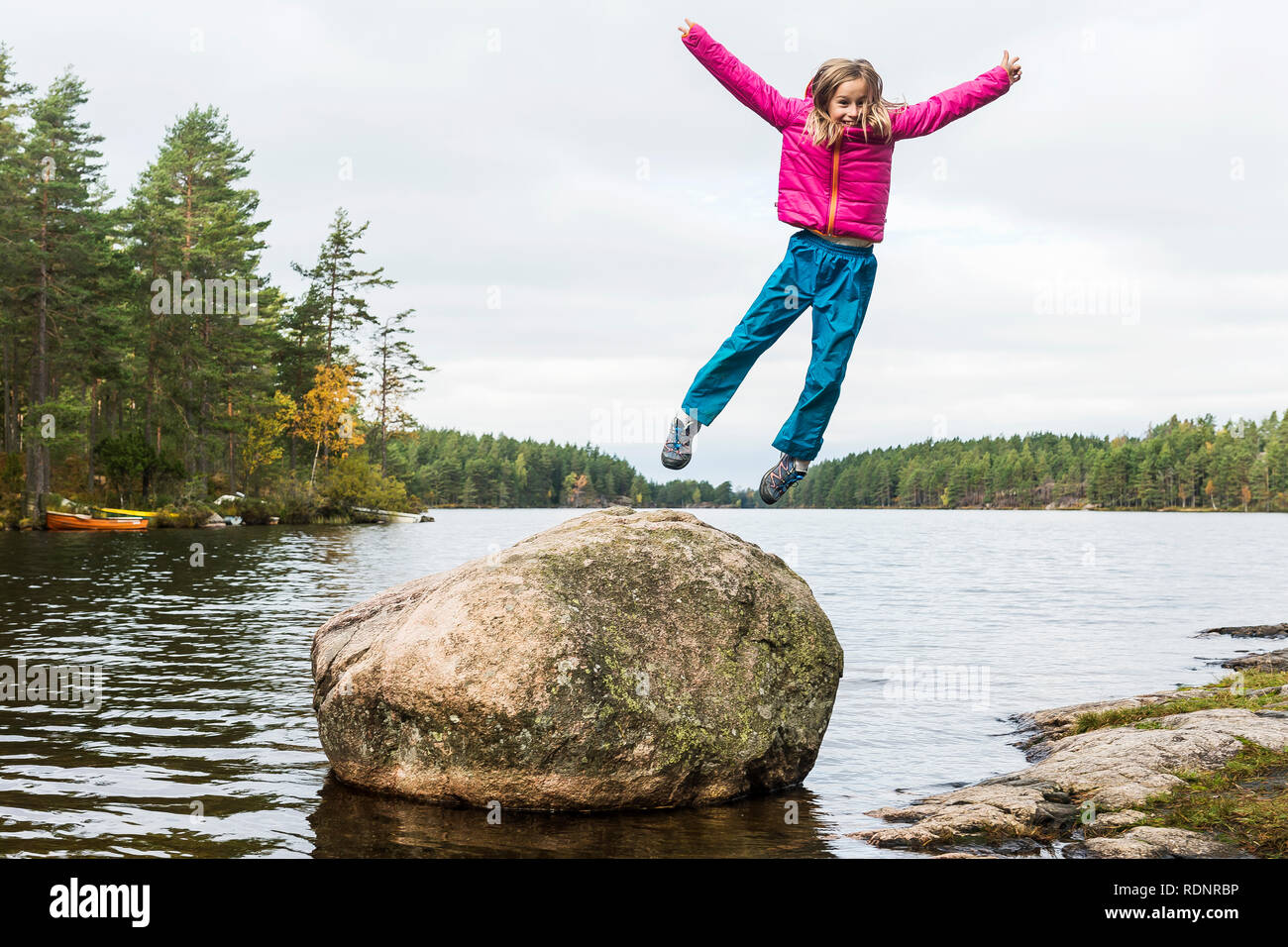 Girl jumping from rock in lake Stock Photo - Alamy