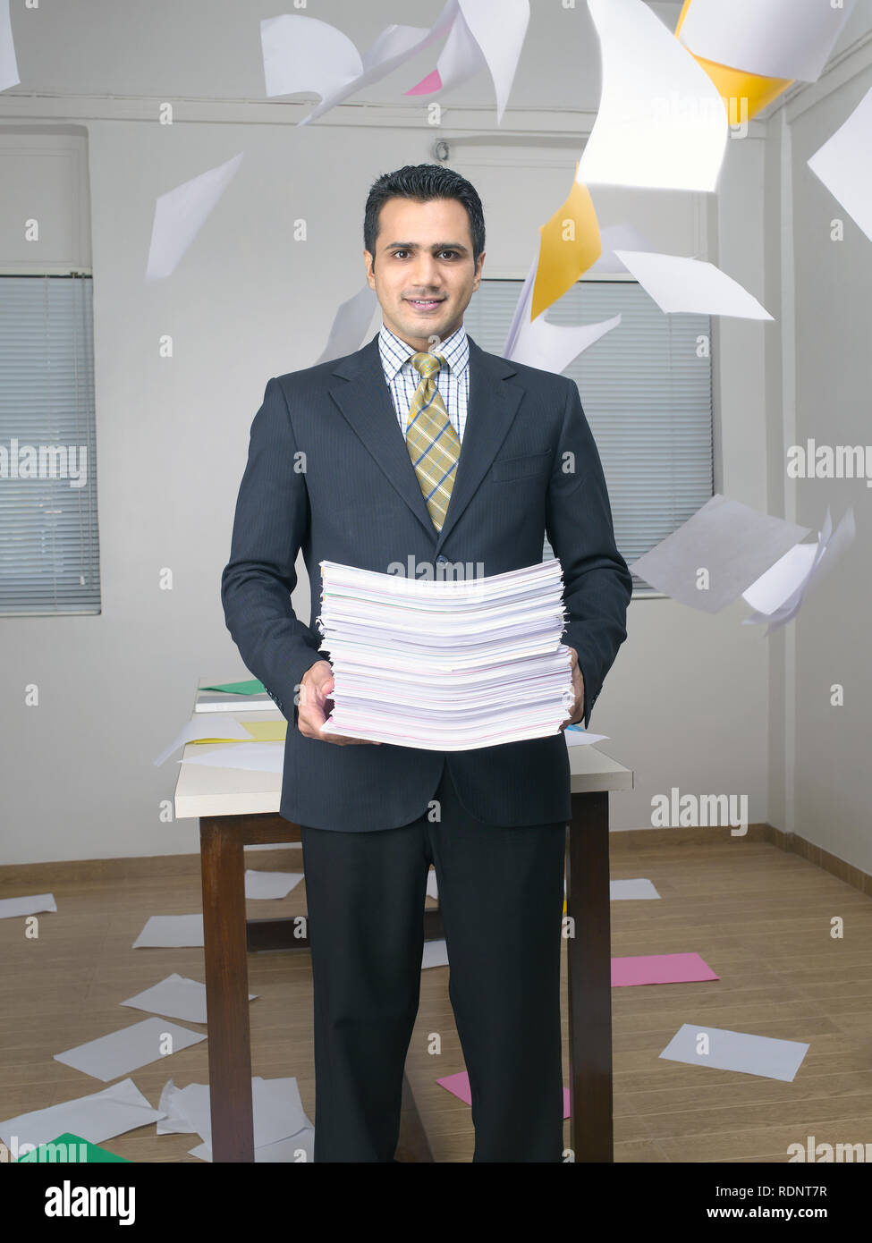 CORPORATE EXECUTIVE HOLDING FILES WITH PAPERS FYLING ALL AROUND HIM ...