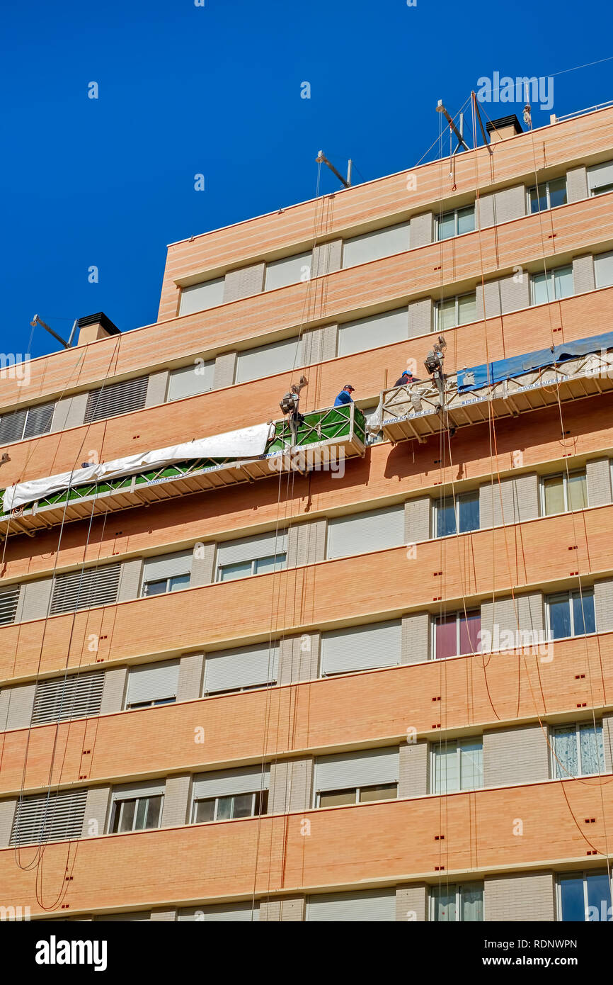 workers on the exterior scaffold elevator to repair the building Stock ...