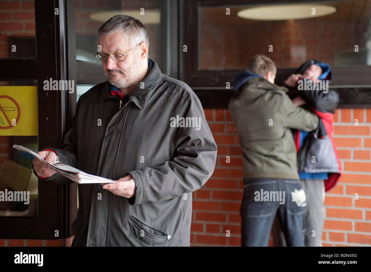 Teacher reading a newspaper while two teenagers are fighting behind his ...
