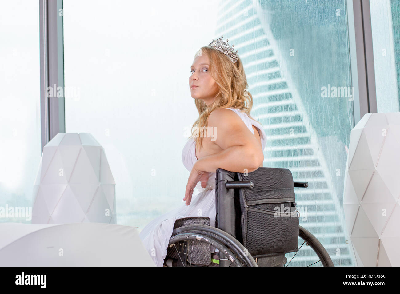 Beautiful disabled bride posing in a wheelchair against the background ...