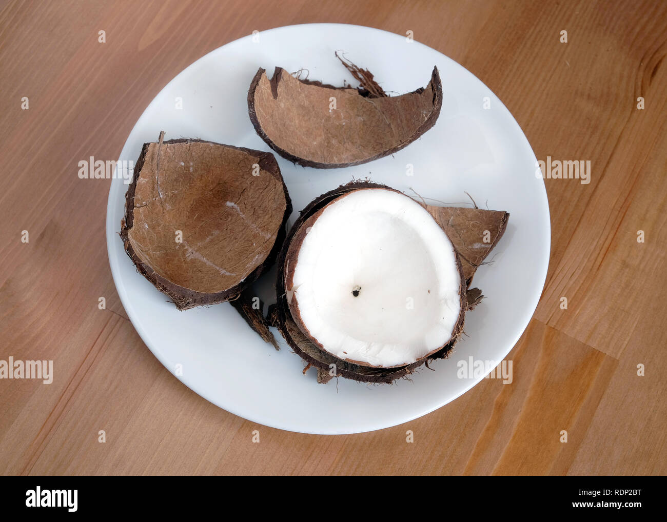 Still life with broken coconut shell ripe white flesh inside and debris ...