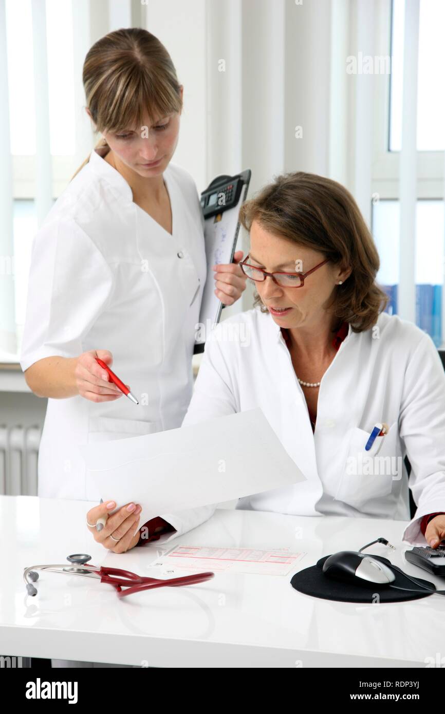 Medical practice, doctor examining the health records of a patient at ...