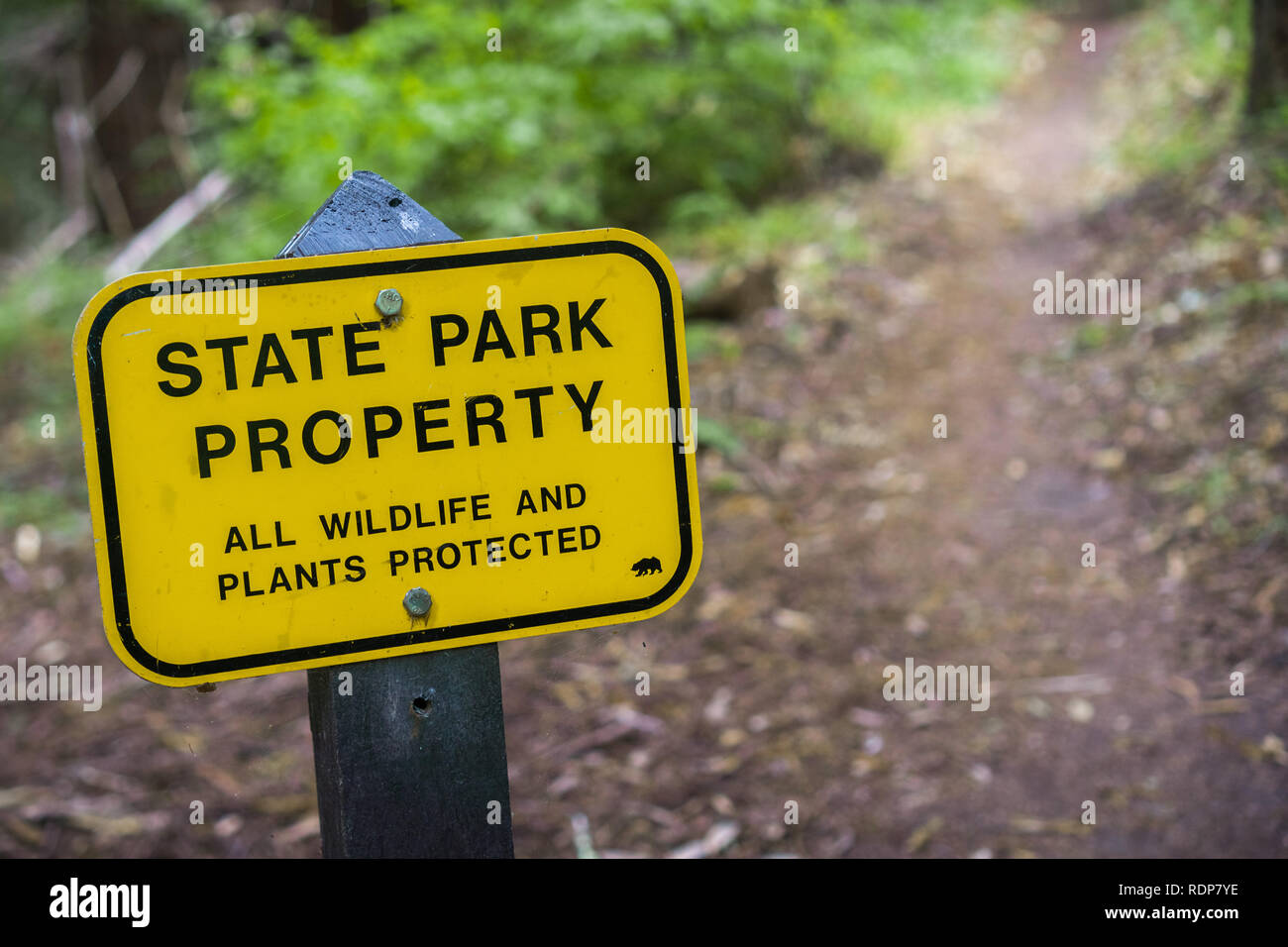 Posted sign at the entrance in a Californian state park; blurred hiking ...
