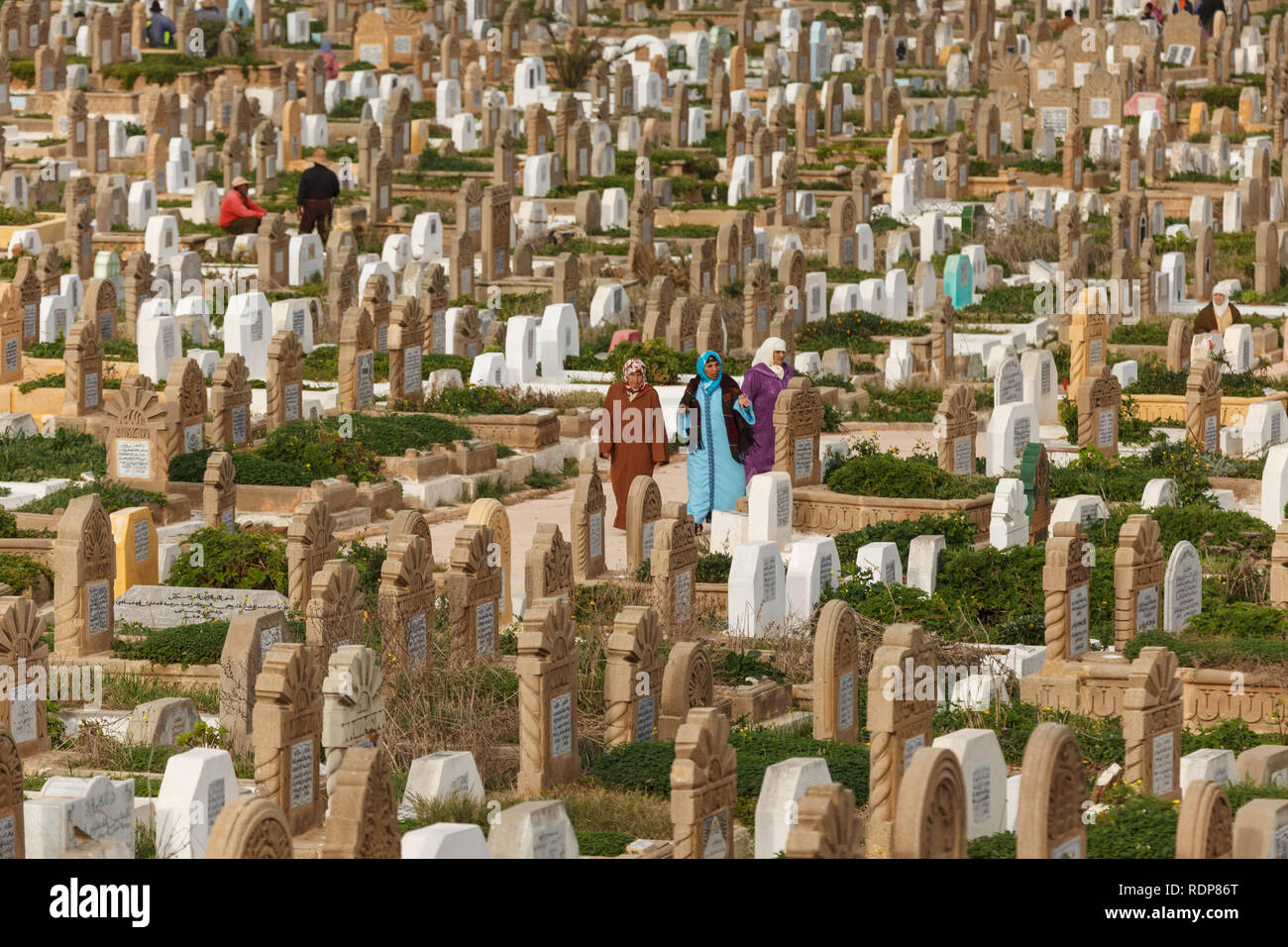 Two women walking in a crowded old Islamic cemetery full of headstones ...
