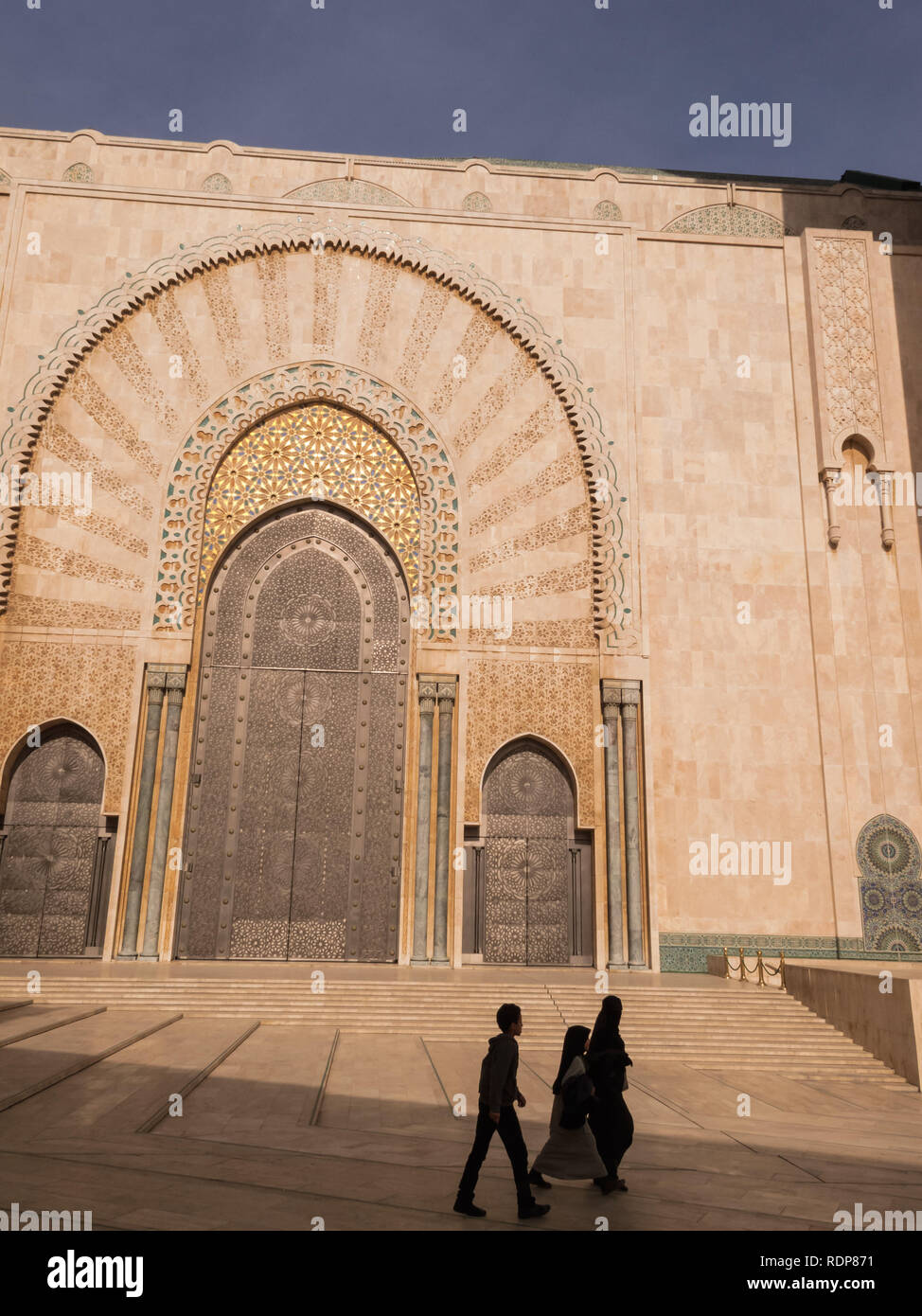 Family walking in courtyard by the gilded gates of a grand mosque Stock ...