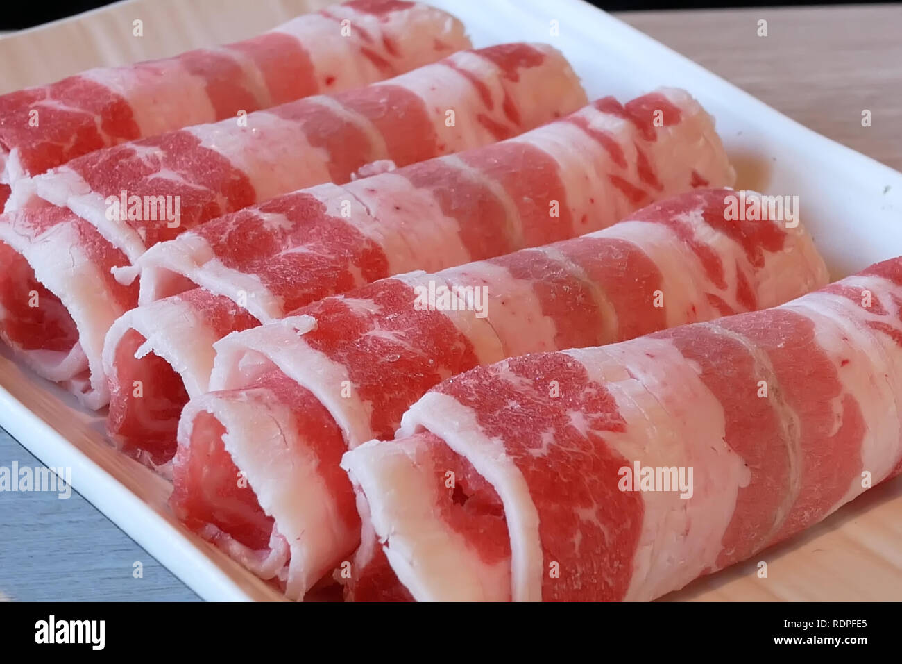 Motion of raw pork meat for hot pot on plate inside Chinese restaurant ...