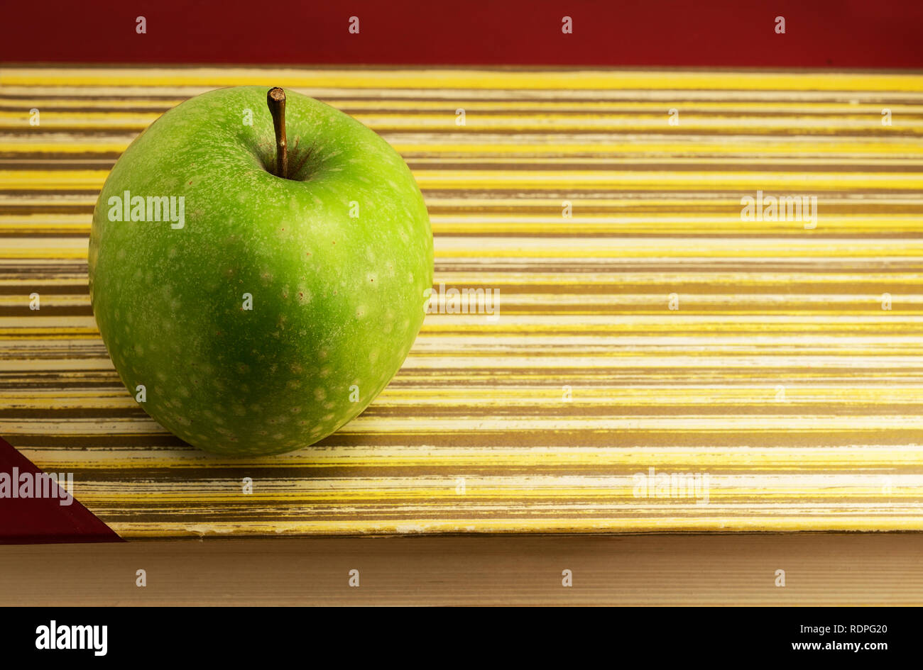 fresh green spotted apple on the striped book Stock Photo - Alamy