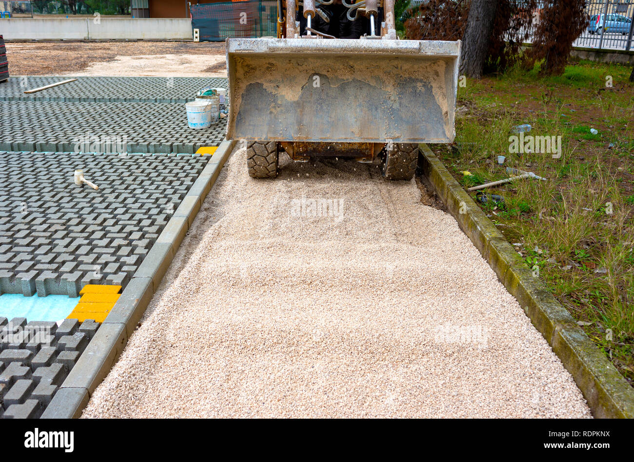 skid loader distributes grit and sand for the background of the ...