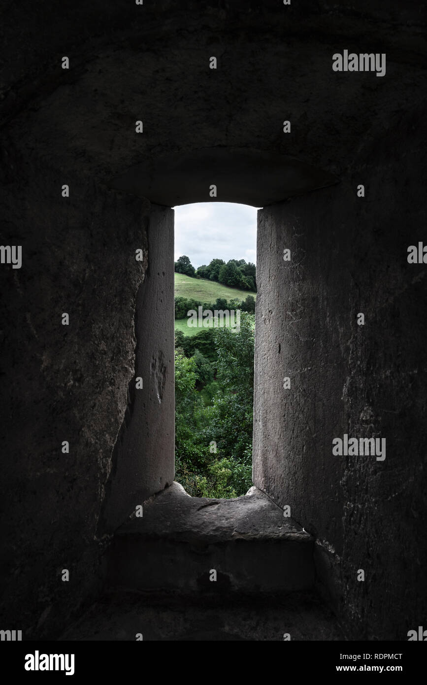 Medieval stone window and green landscape with forest and meadow viewed ...