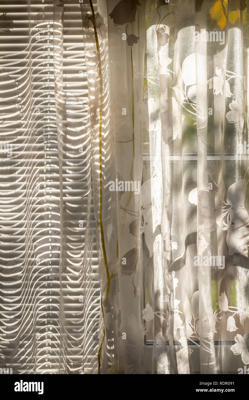 The sun's rays make their way through the closed blinds to the curtain ...