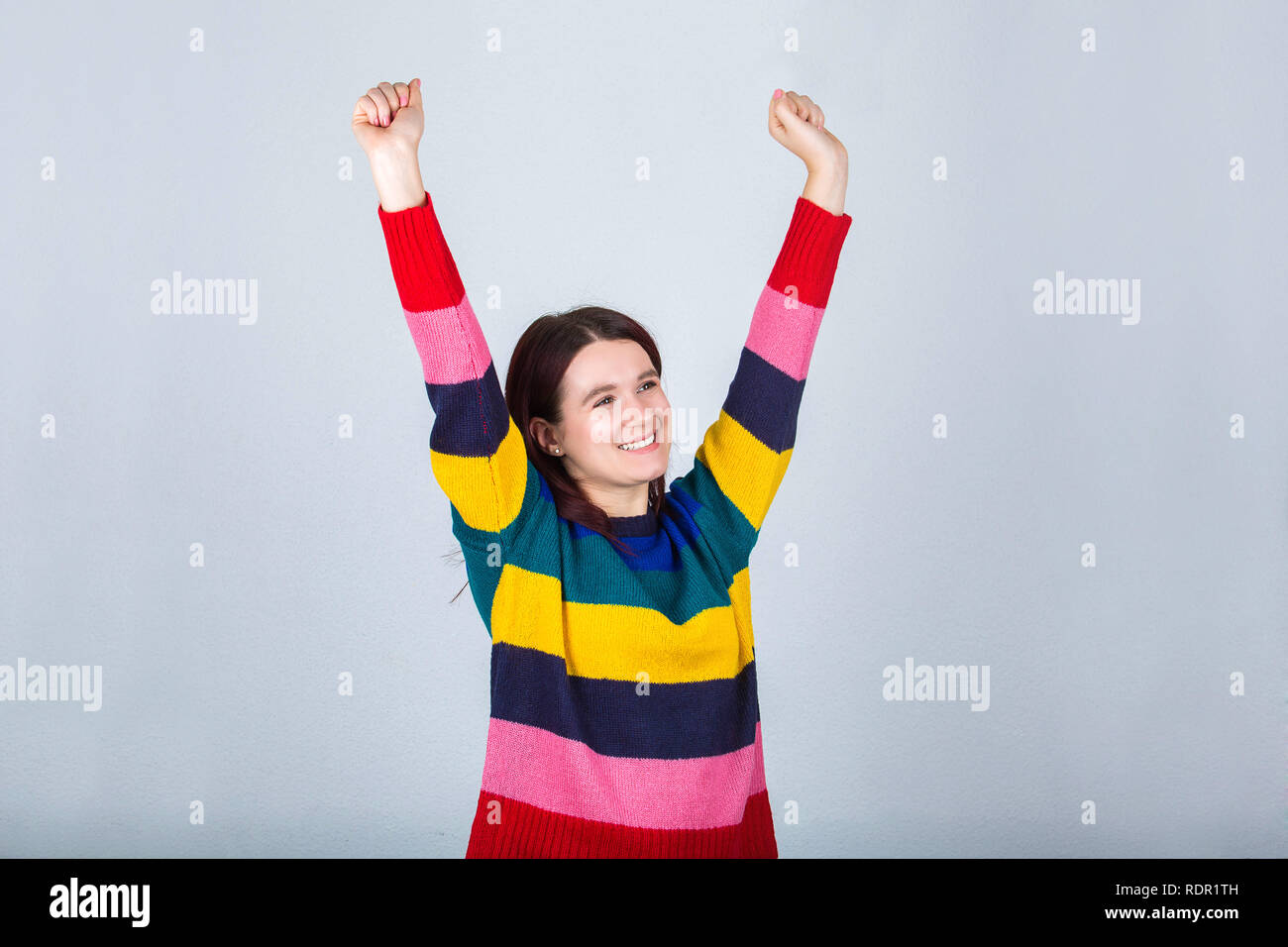 Cheerful young woman celebrating victory as raising hands up sign of ...