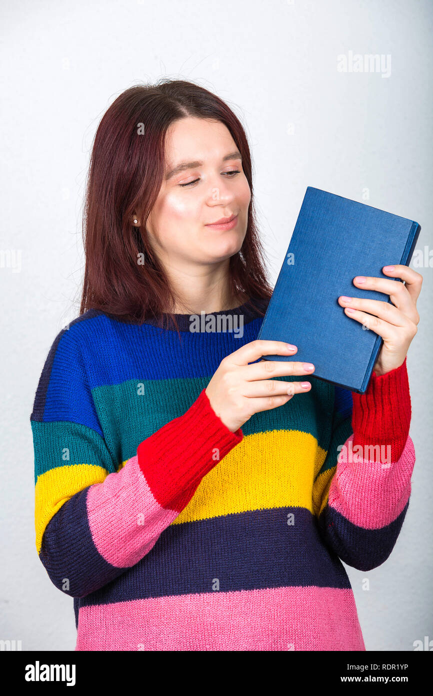 Young woman student holding a book in her hands looking attentive ...
