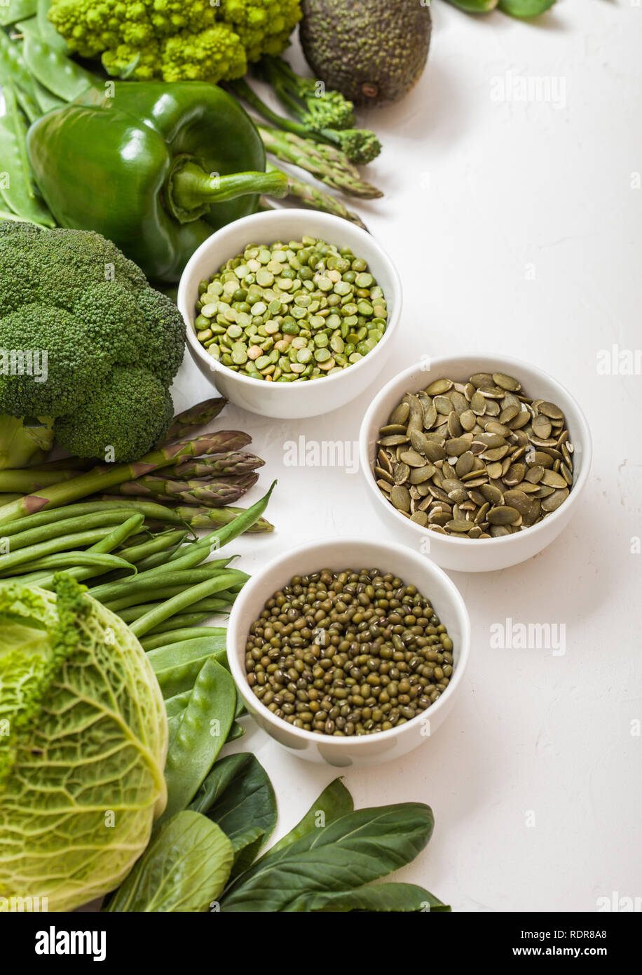 Assorted green toned raw organic vegetables on white background ...