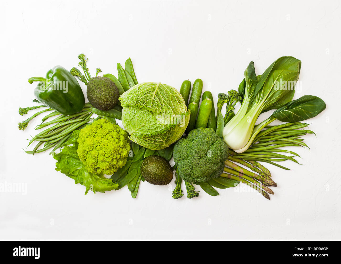 Assorted green toned raw organic vegetables on white background ...