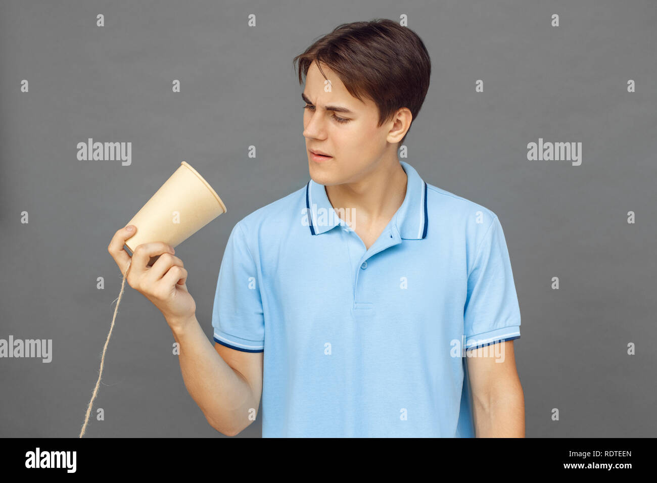 Freestyle. Teenager boy standing isolated on grey looking at string ...
