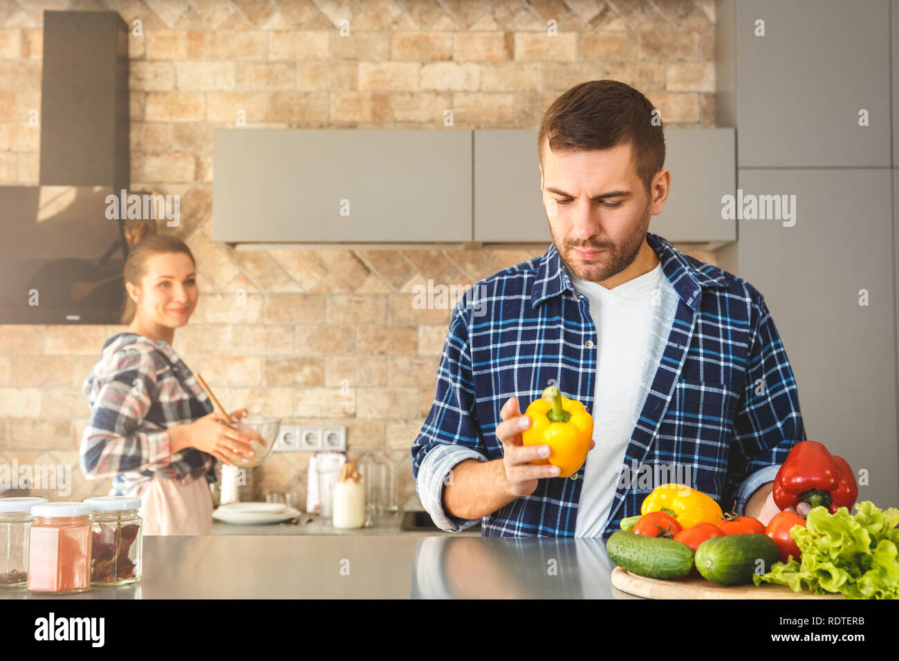 Young couple at home standing in kitchen together man holding bell ...