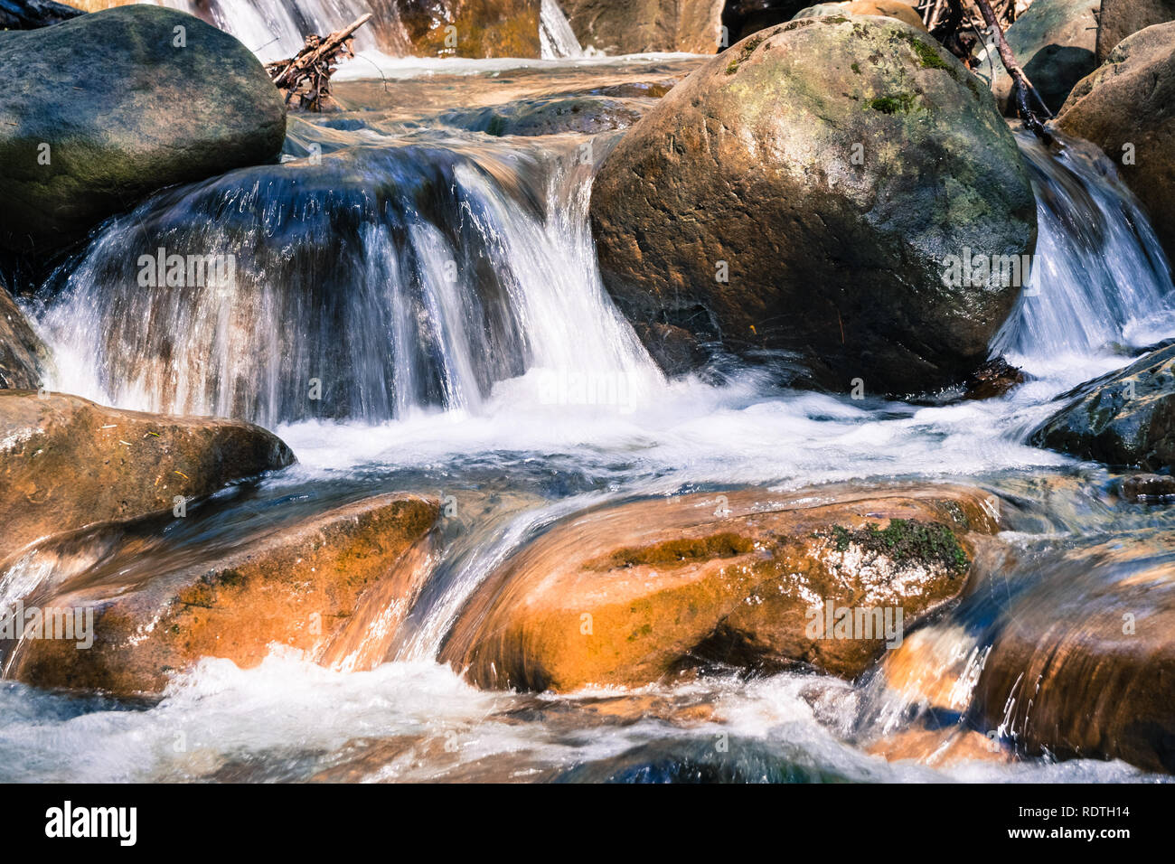 Close up of water falling through rocks on the course of a creek in ...