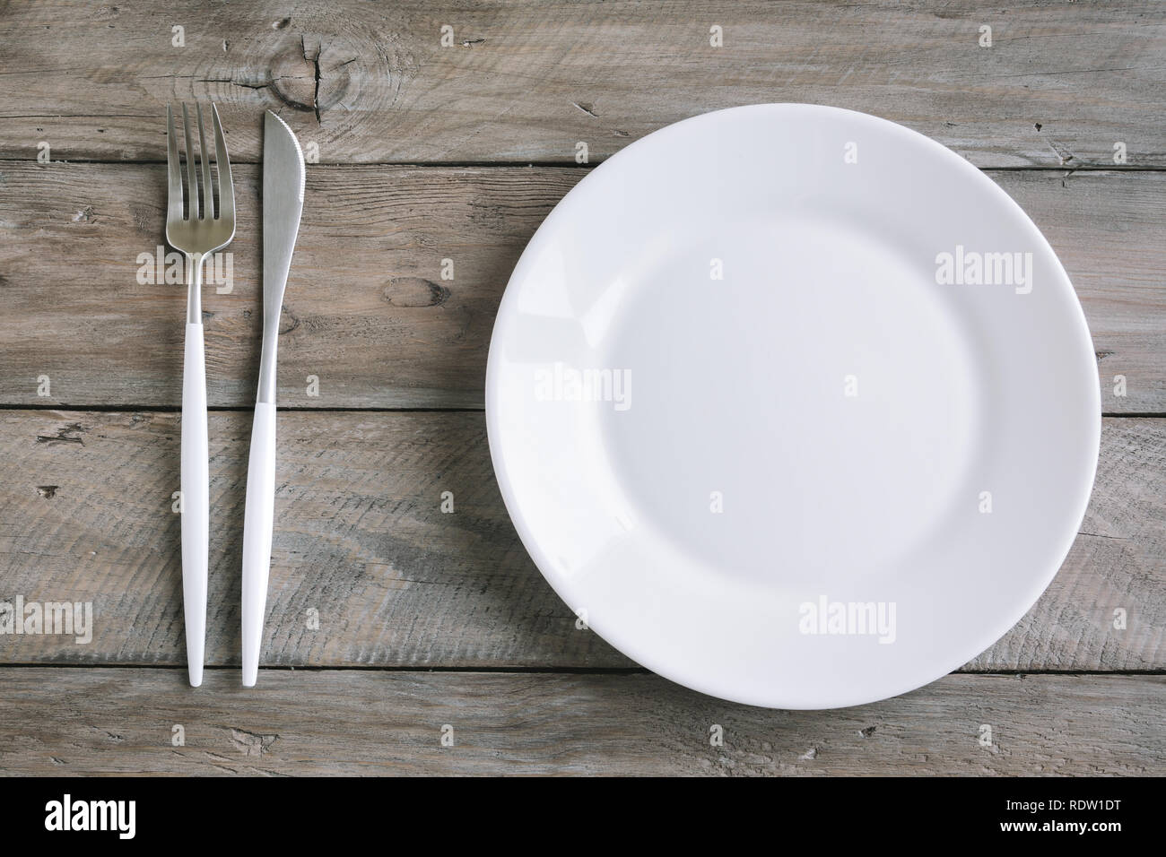Empty table setting - plain white ceramic plate, cutlery on wooden ...
