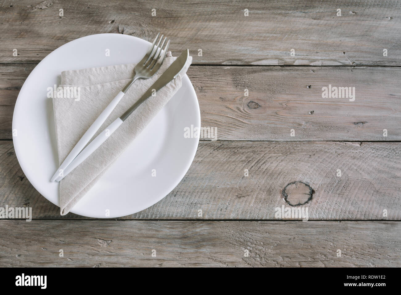 Empty table setting - plain white ceramic plate, linen napkin, cutlery ...