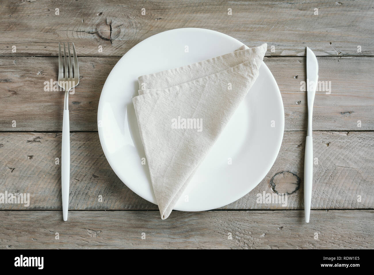 Empty table setting - plain white ceramic plate, cutlery on wooden ...