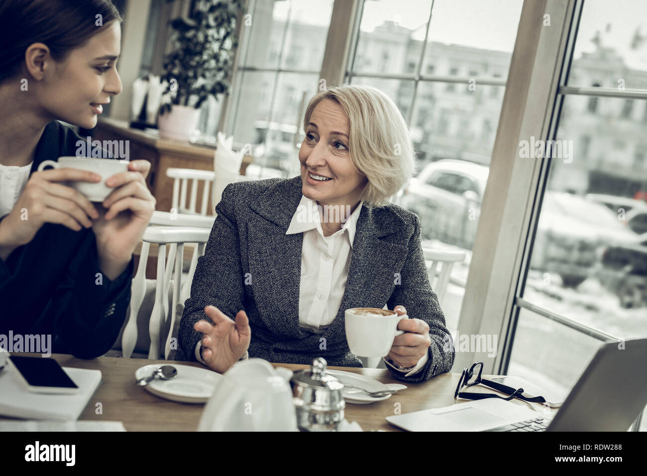 Mother and daughter feeling relieved and rested drinking coffee ...