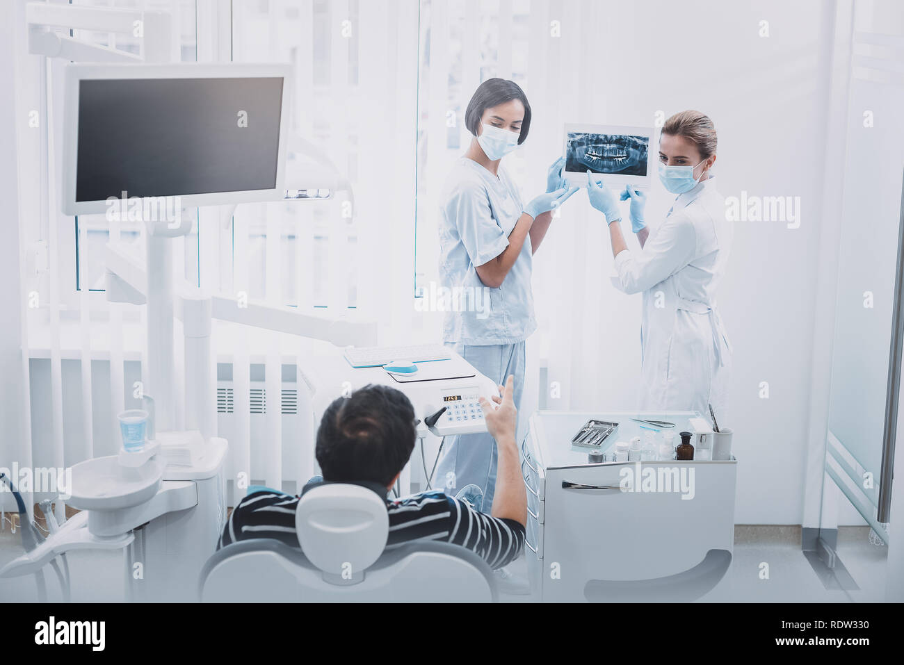 Cheerful young international dentist demonstrating roentgen picture ...