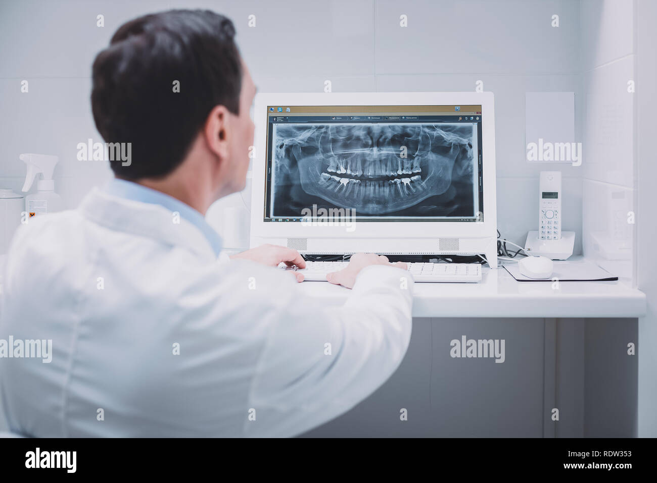 Professional dentist staring at screen of computer Stock Photo - Alamy
