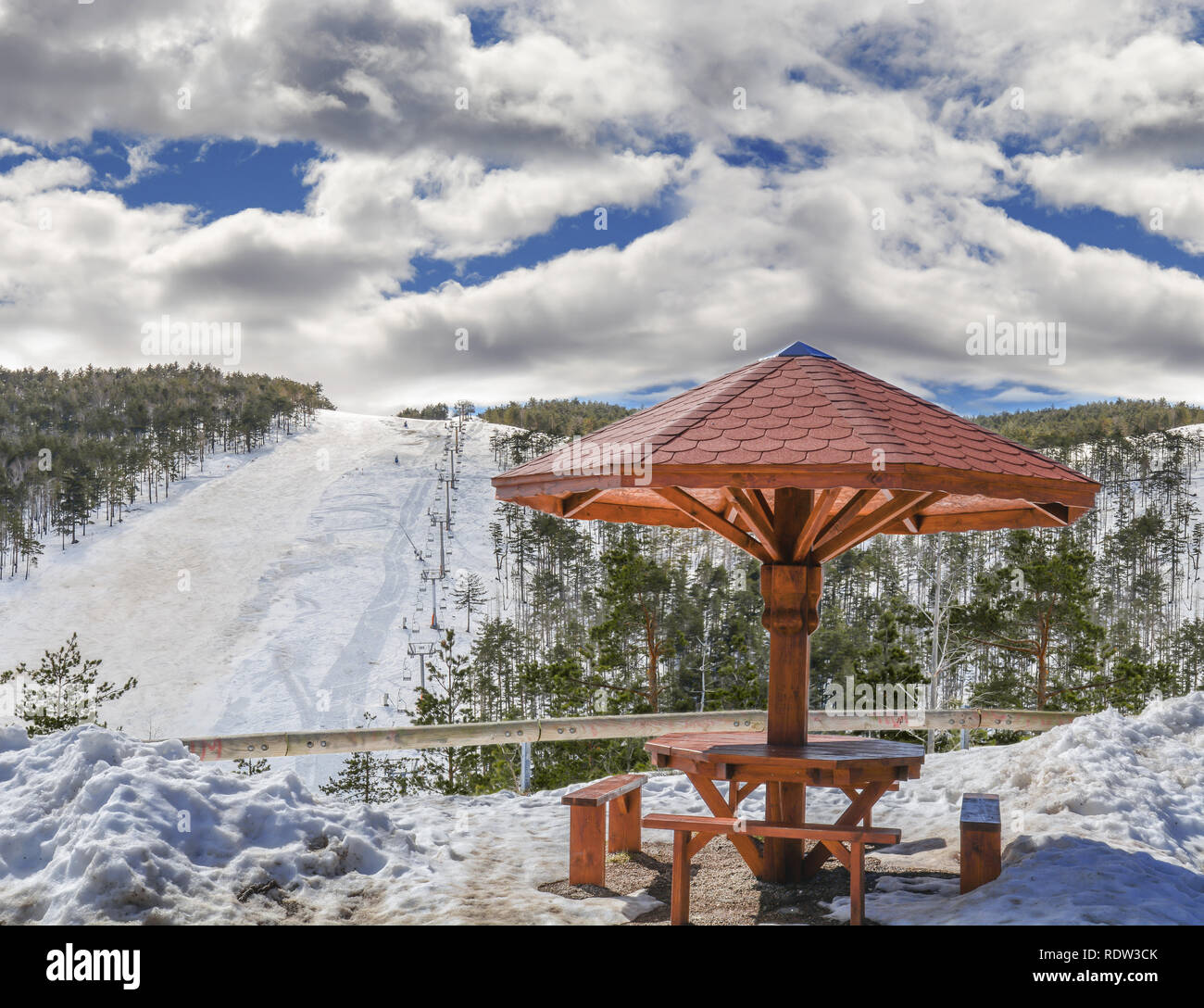 Wooden bench with roof and snow on mountain view ski track point with ...