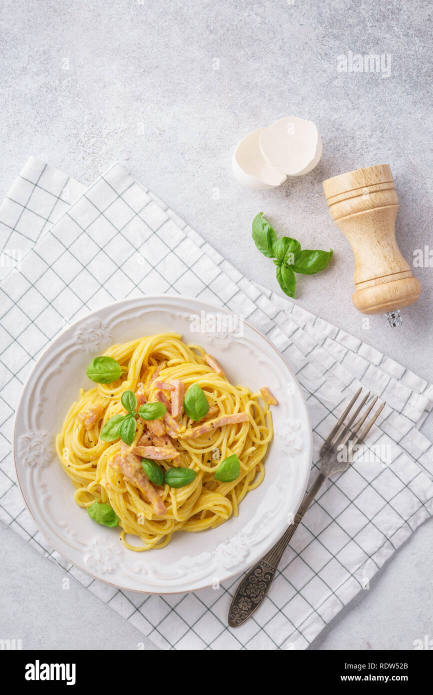 Italian pasta carbonara with ham, basil and eggs on a light grey ...