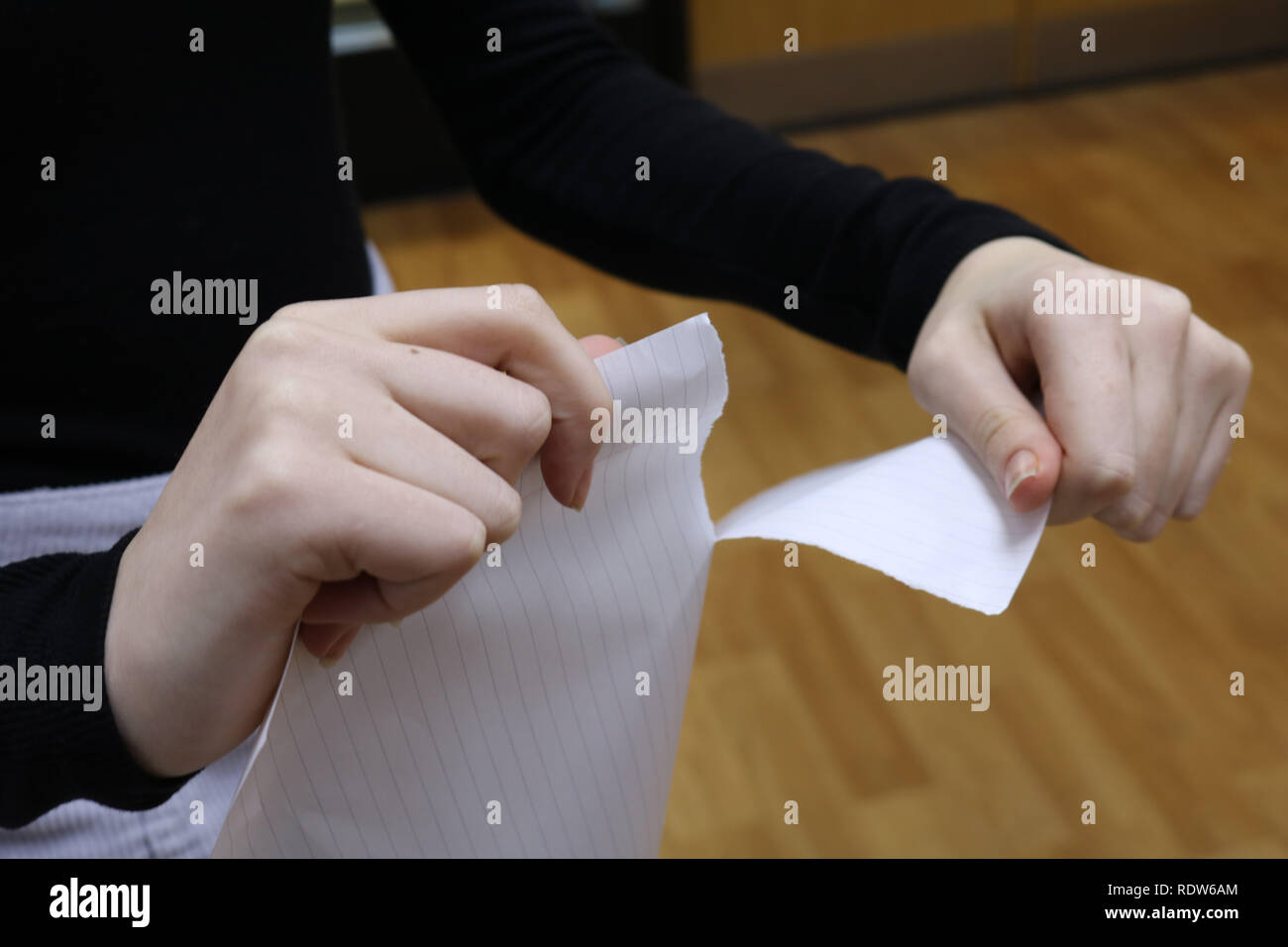 Hands ripping lined paper in half horizontally Stock Photo - Alamy