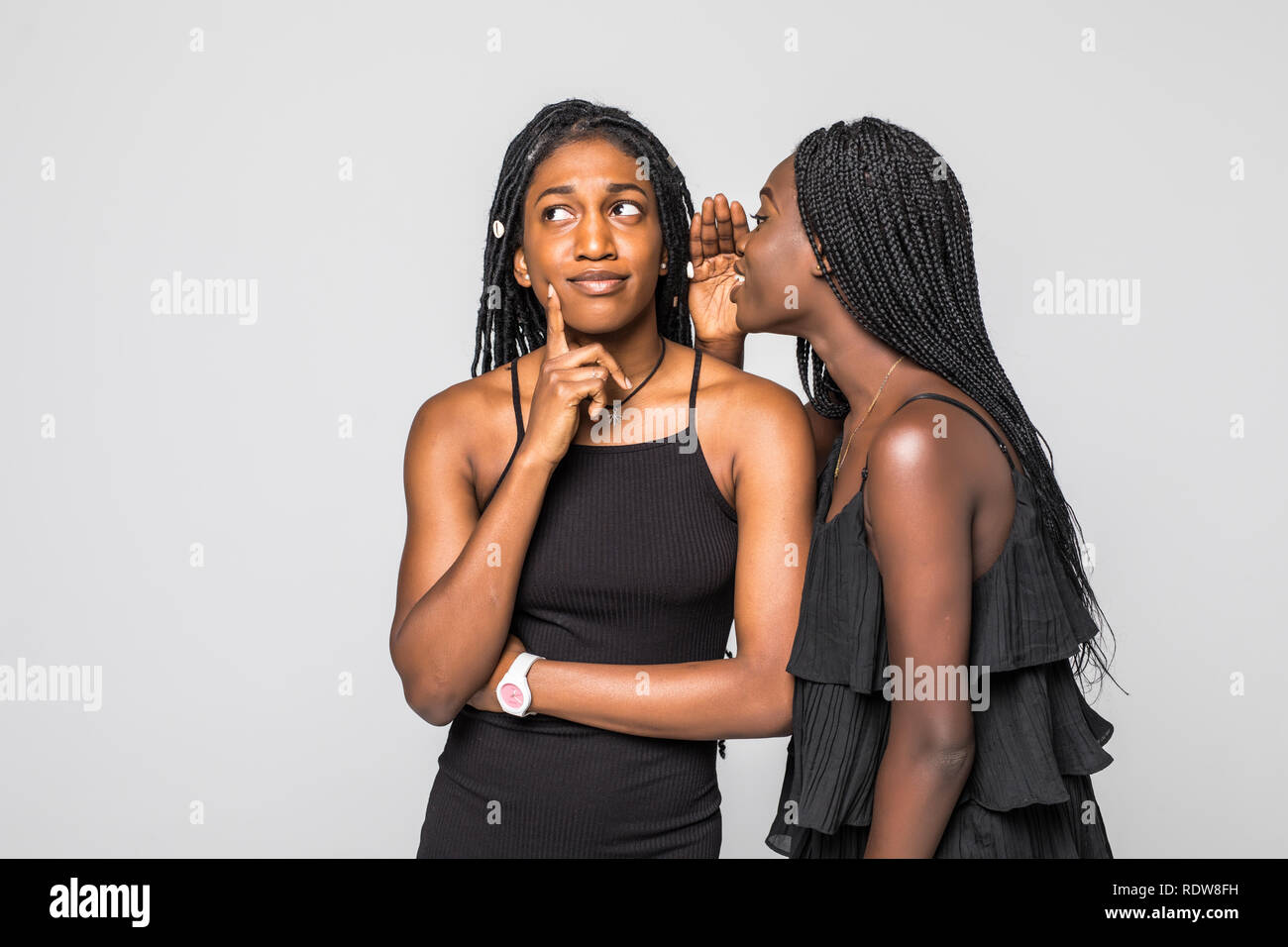 Portrait of two happy young african women sharing secrets isolated ...