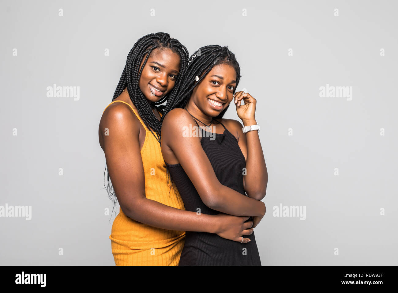 Portrait of two african women in dresses hugging over gray background ...