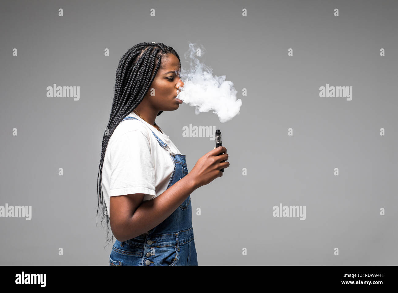 Side view portrait of guy holding vape device and exhaling cloud of ...