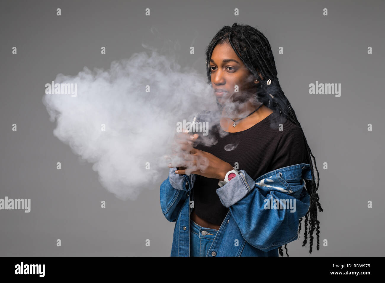 Young african woman holding and vaping an electronic cigarette, e-cig ...