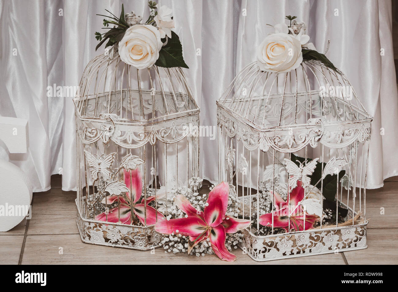 Wedding decoration. Two old ornamental cages decorated with colorful ...
