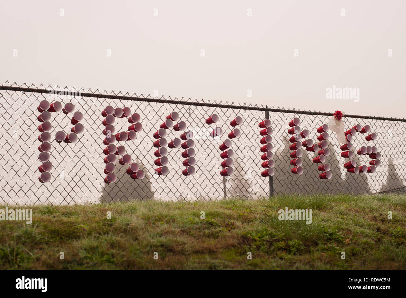 Red cups spelling the word praying on chain link fence after highschool ...