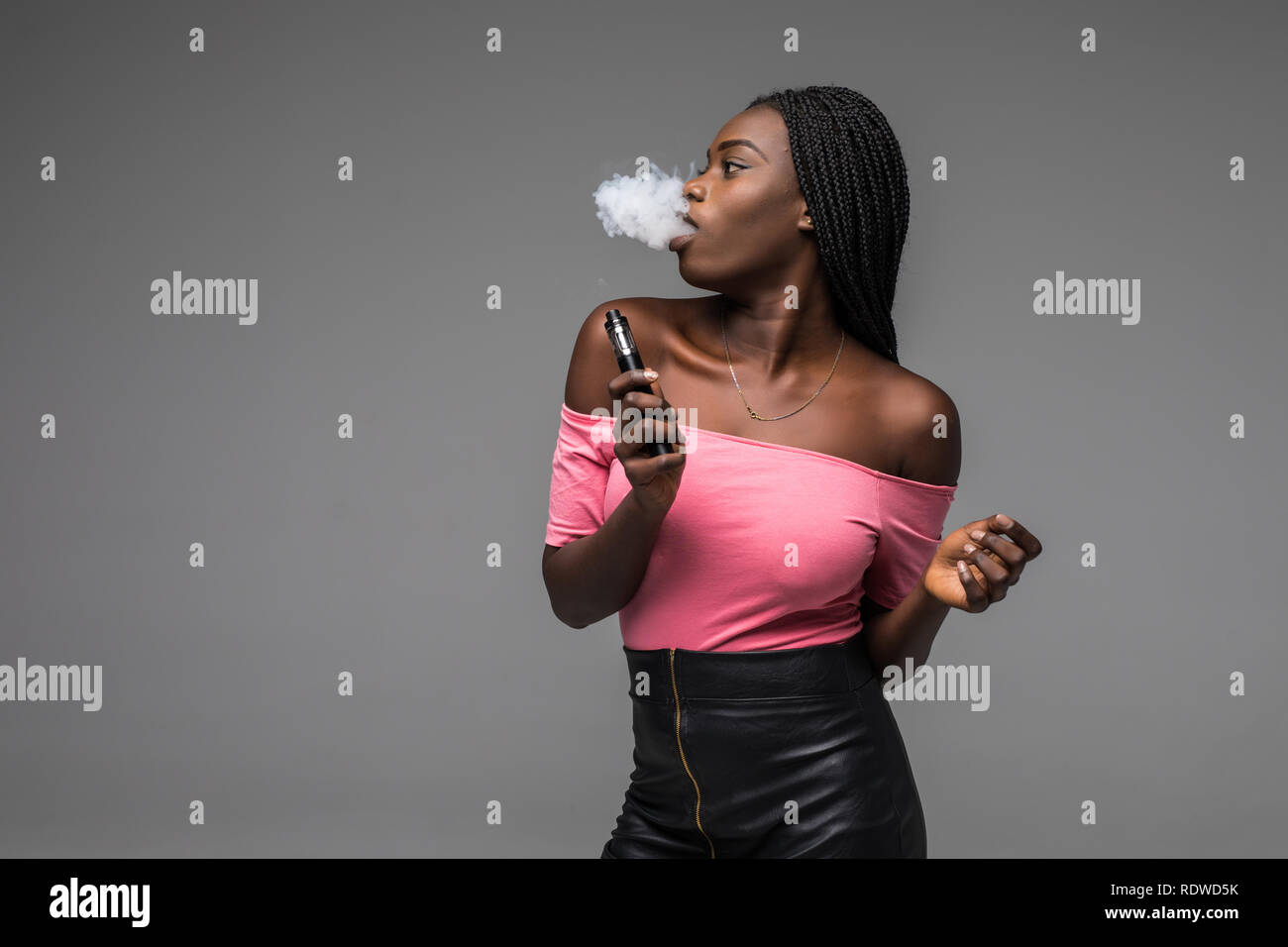 African woman smoking or vaping e-cig or electronic cigarette holding a ...