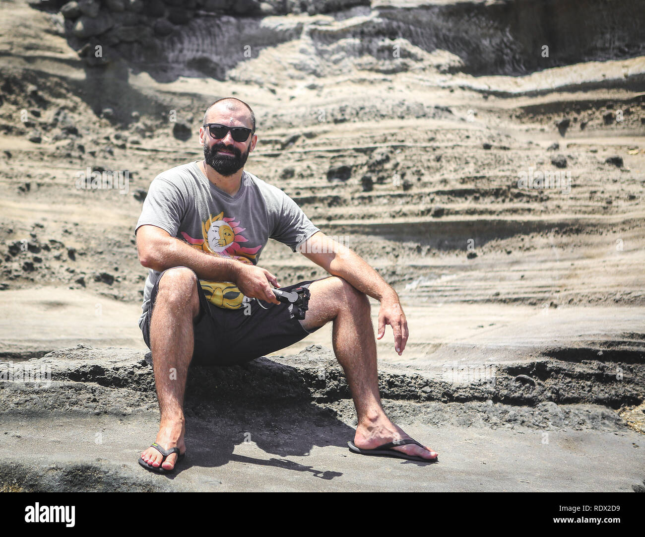 Young man with beard siting on the sandy desert bank Bali Indonesia ...
