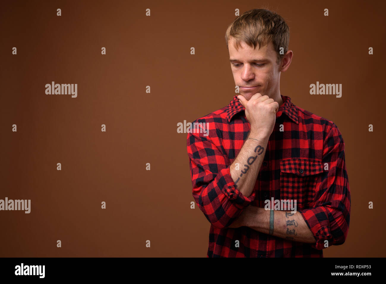 Man wearing red checkered shirt against brown background Stock Photo ...