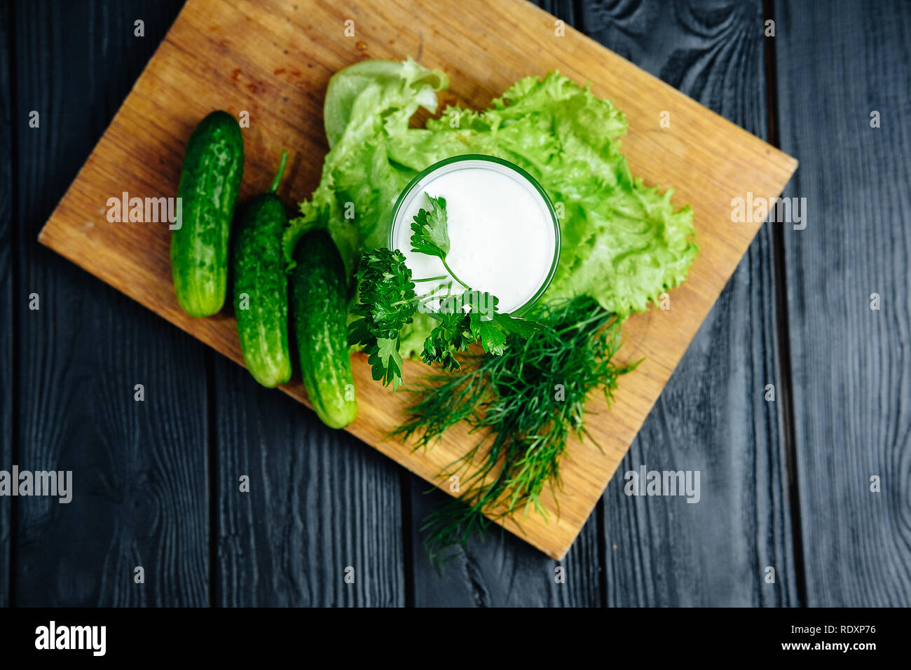 Fresh plain homemade yougurt with cucumber herbs over dark background ...