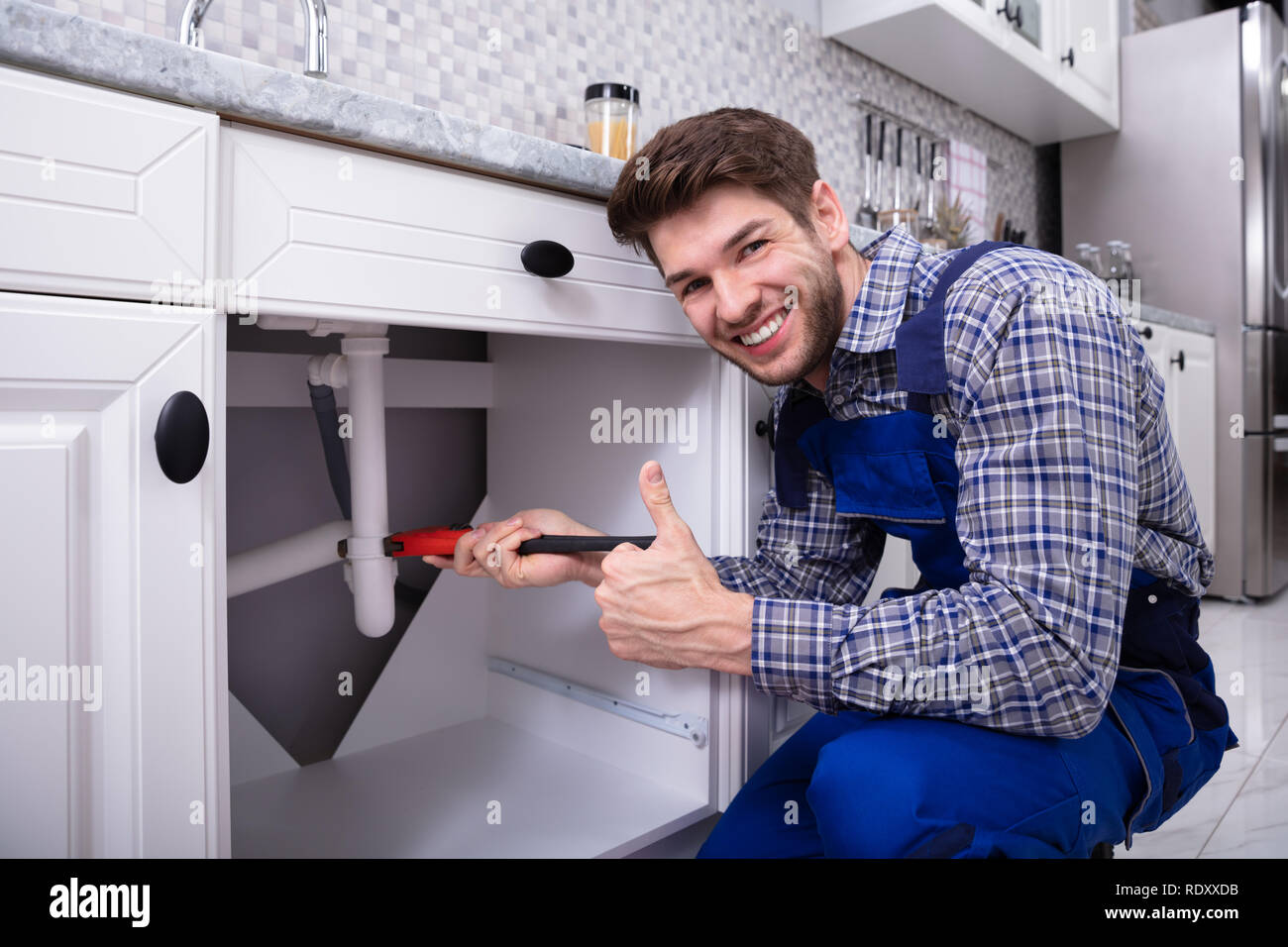 Young Male Plumber Repairing Sink Pipe With Adjustable Wrench Stock ...