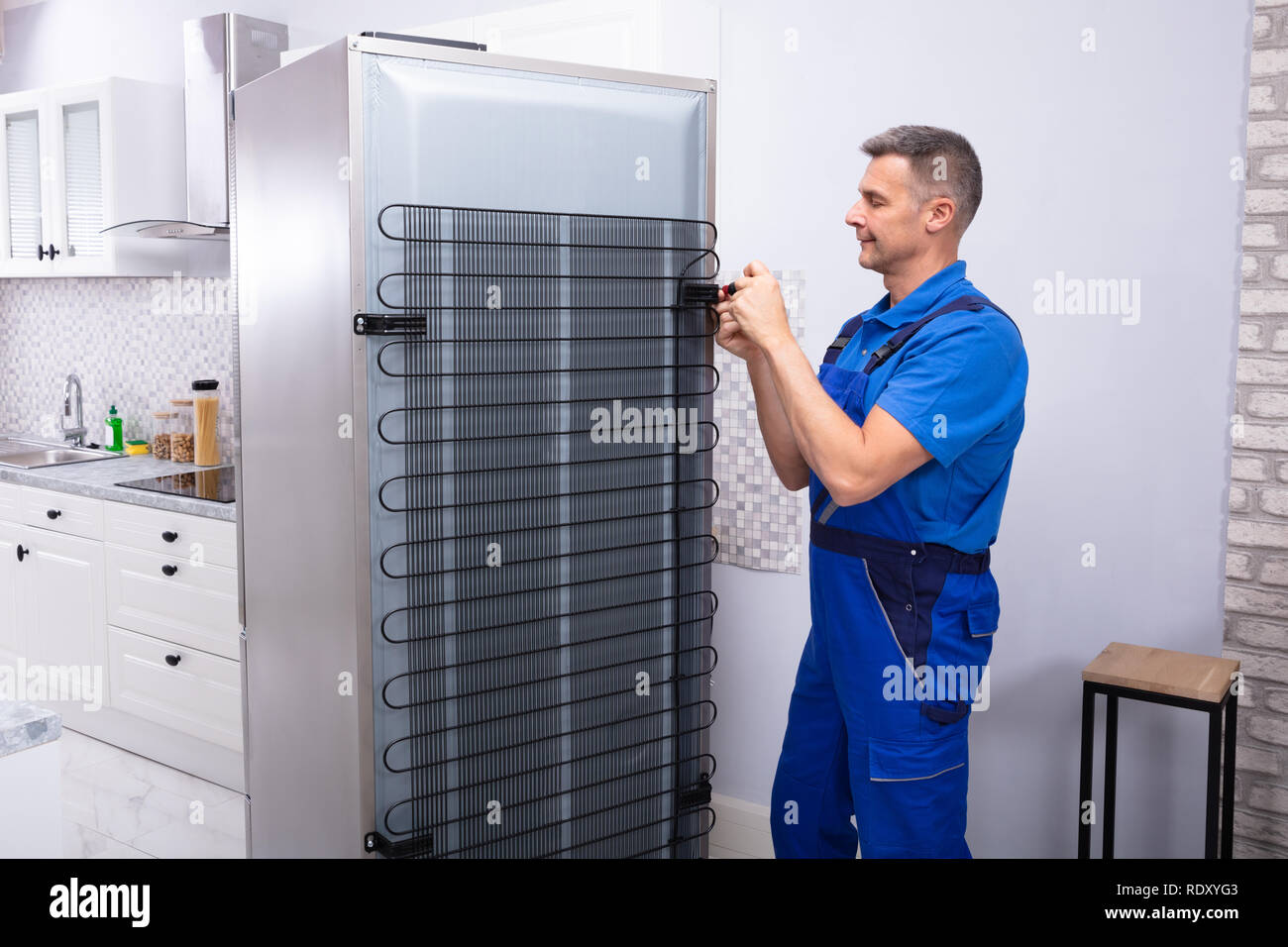 Electrician working on fridge in home hi-res stock photography and ...
