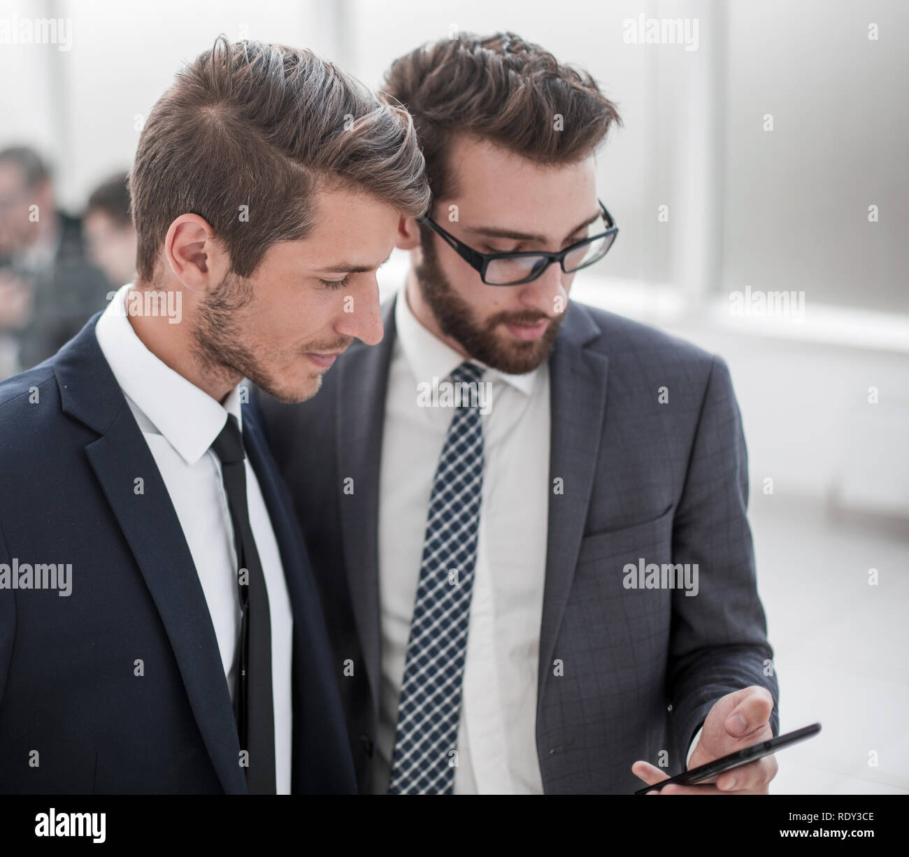 two employees looking at the smartphone screen Stock Photo - Alamy