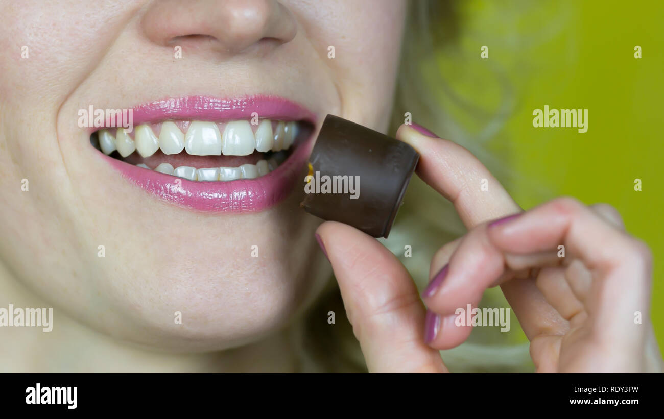 Candy cane near female mouth. The girl brings sweet candy to her mouth ...