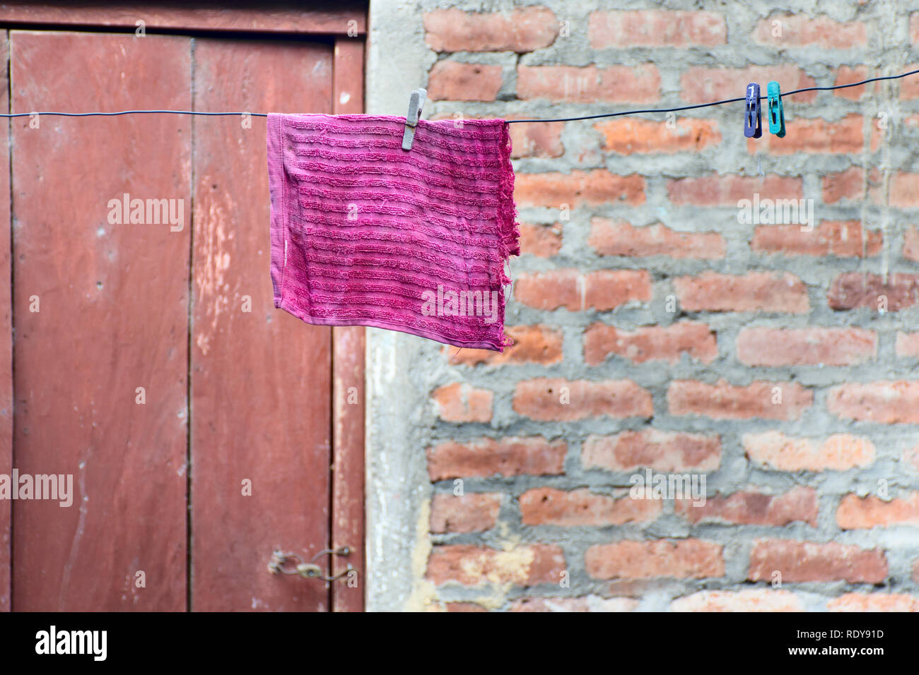 A street view in Nicaragua - a worn out red rag is drying on a wire ...