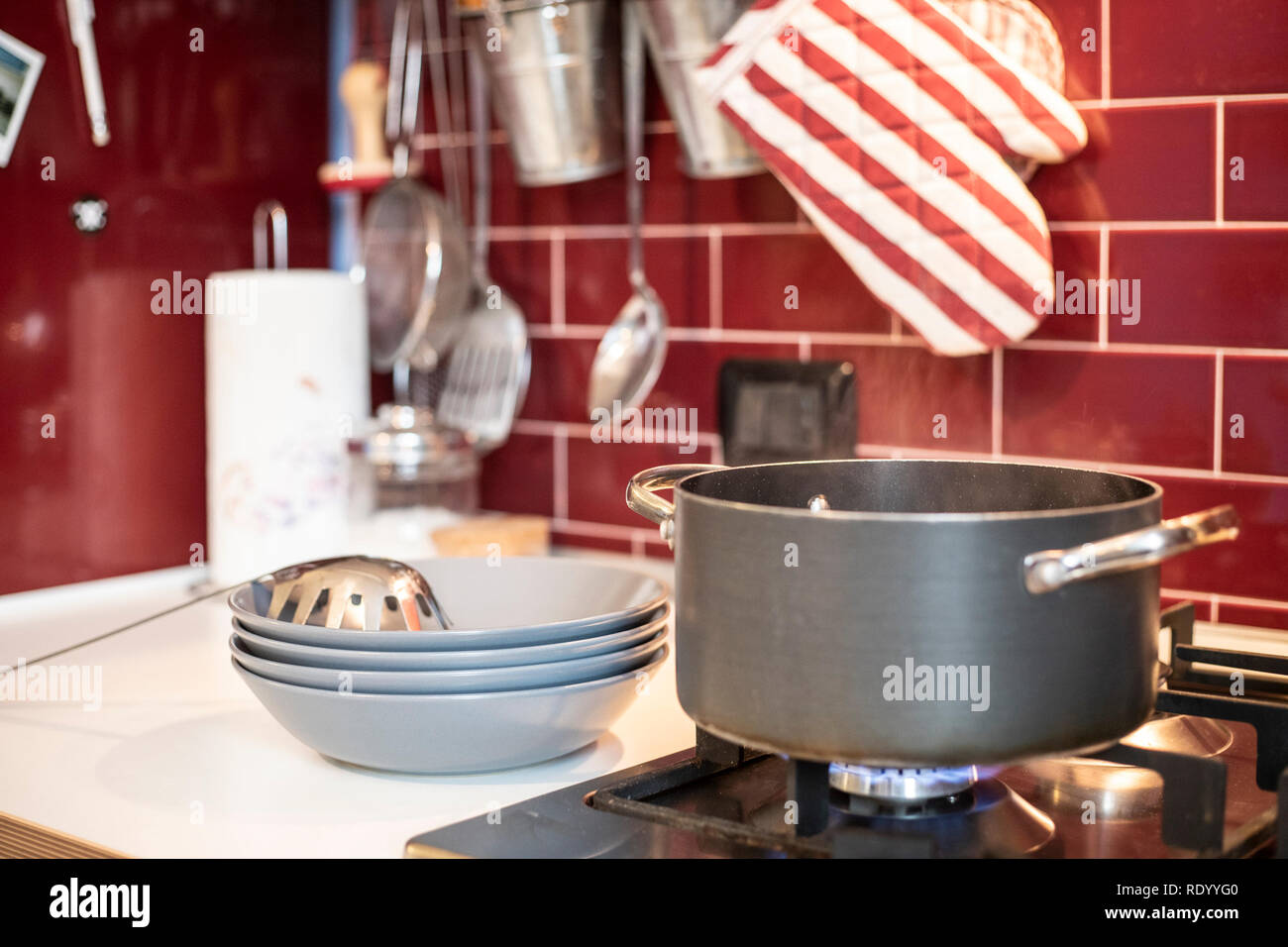 grey cooking pot on gas stove with steam releasing and blue dishes on ...