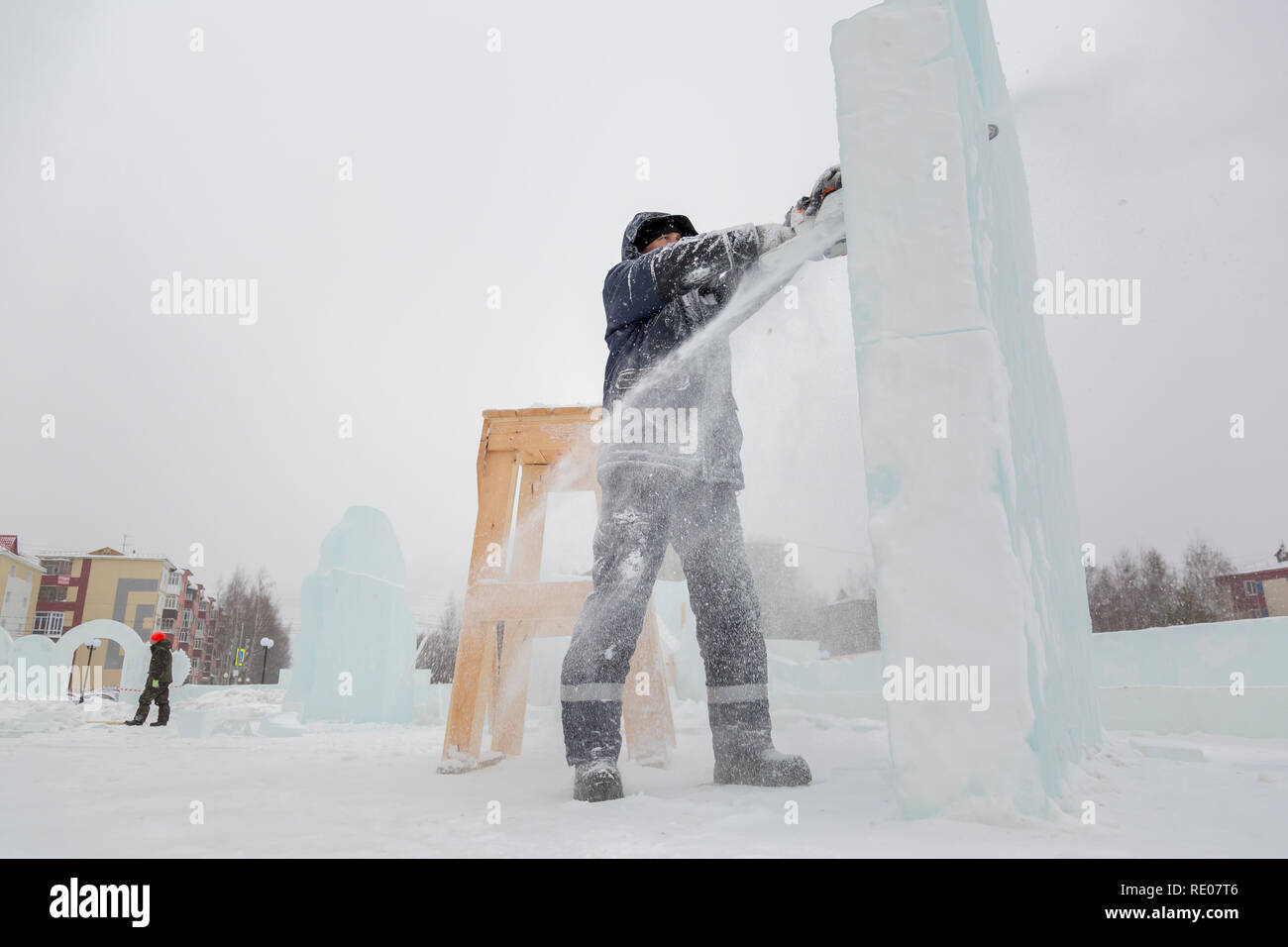 The sculptor cuts an ice figure out of ice by a chainsaw for Christmas ...