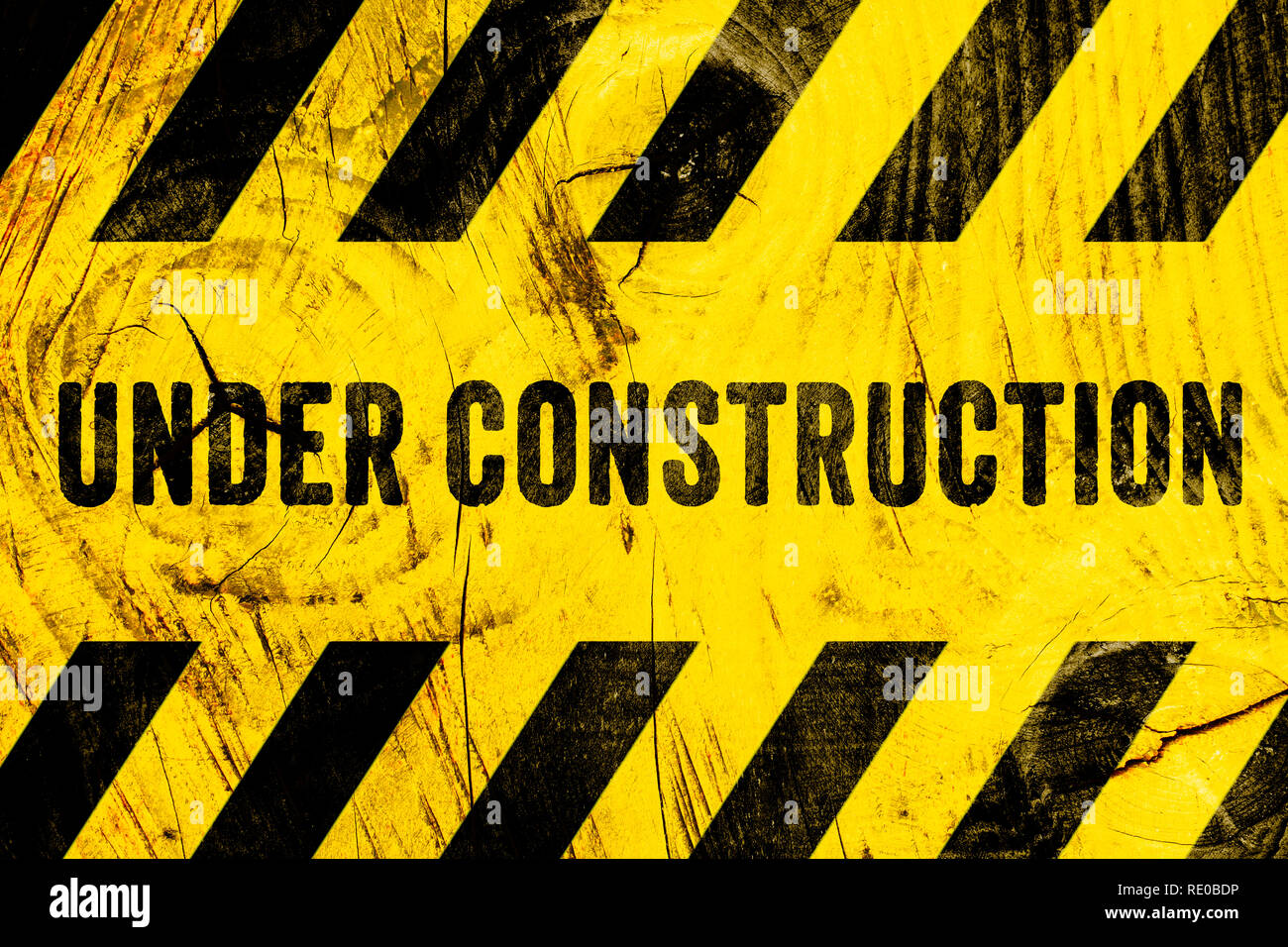 Under construction warning sign text with yellow black stripes painted ...